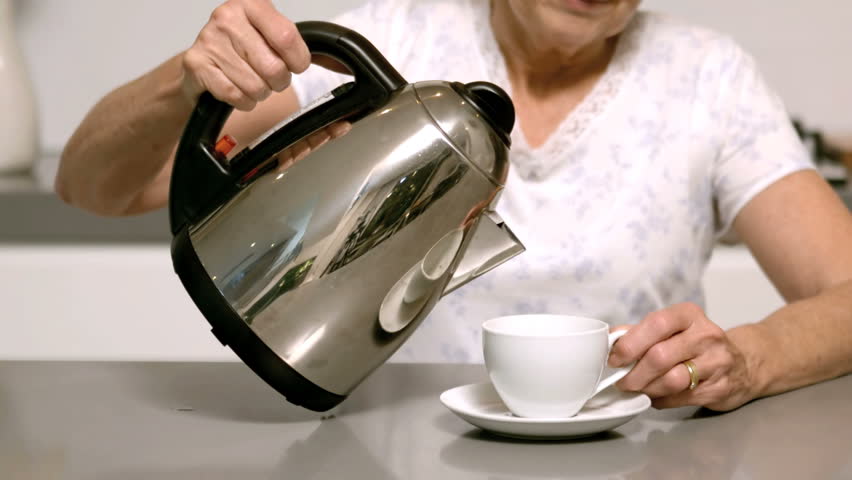 Retired Woman Pouring Boiling Water From Kettle Into Cup In Slow Motion ...